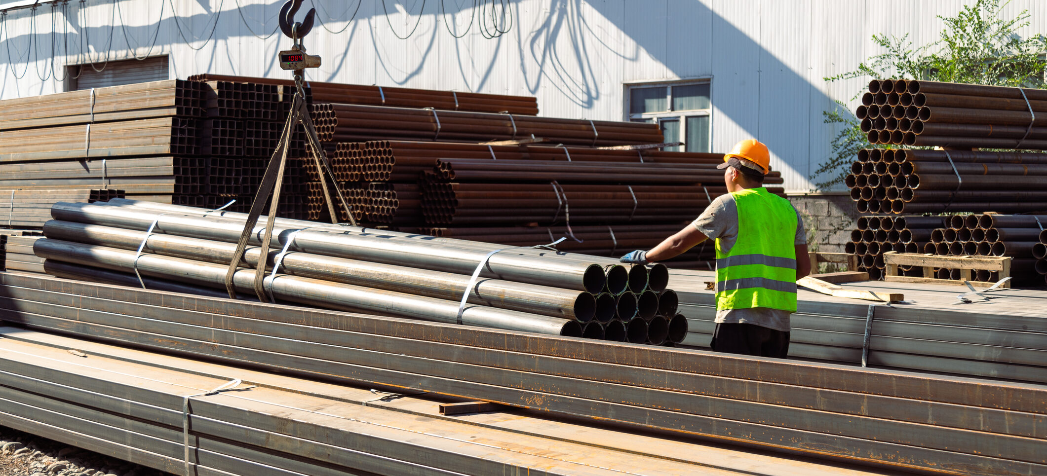 Worker transporting stack of metal pipes with gantry crane - Blue Peak ...